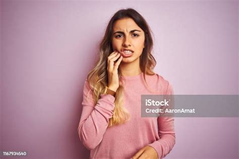 분홍색 고립 된 배경 위에 스웨터를 입은 젊은 아름다운 여성은 치아에 치통이나 치과 질환으로 인해 고통스러운 표정으로 입을