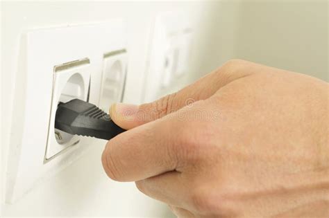 man plugging in or unplugging an electrical plug in a socket stock