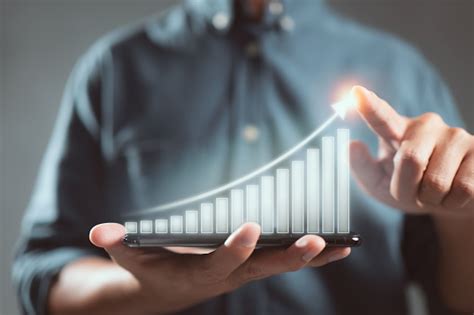 비즈니스 맨은 휴대 전화를 보유하고 수익성 그래프의 통계를 보여주는 그래픽 그래프를 표시 성장 계획의 아이디어와 좋은 비즈니스의 동향을 볼 수있는 비즈니스 전략 성장 개념에