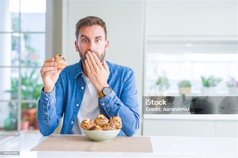 잘생긴 남자 먹는 초콜릿 칩 머핀 커버 입으로 실수에 대 한 수치와 충격 두려움의 표현 침묵에 무서 워 비밀 개념 남자에 대한 스톡 사진 및 기타 이미지 Istock