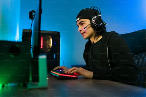 젊은 라틴 남자가 헤드폰과 마이크를 가지고 온라인 플레이어나 친구에게 비디오 게임을 하는 동안 이야기한다 사진