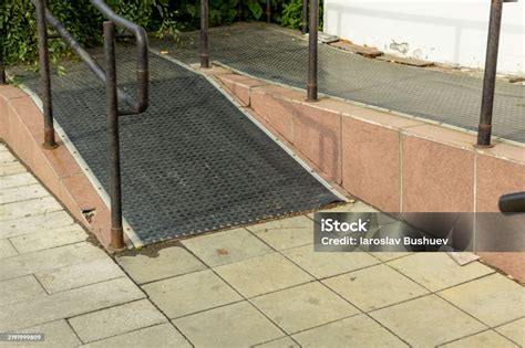 접근성을 위해 설계된 경사로는 잘 관리된 도시 환경에서 주변 타일 통로와 난간이 있는 건물로 이어집니다 0명에 대한 스톡 사진 및 기타 이미지 Istock