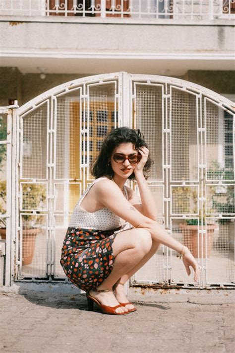 게이트 옆에서 야외 포즈를 취하는 패셔너블한 여성 · 무료 스톡 사진