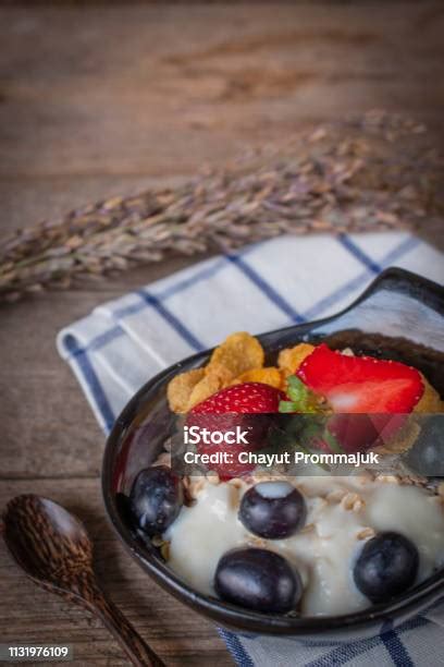 요구르트 믹스 오트밀 딸기 포도 토 핑에 검은 그릇에 파란색과 흰색 줄무늬 직물 및 나무 테이블에 숟가락 옆에 배치 합니다 0명에 대한 스톡 사진 및 기타 이미지 Istock