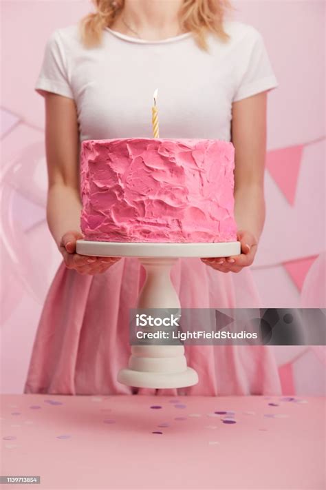 달콤한 분홍색 생일 케이크와 불타는 촛불을 가진 여자를 들고 케이크 스탠드의 자른 보기 단일 이미지에 대한 스톡 사진 및 기타