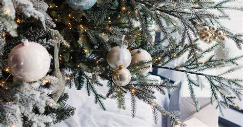 은색 싸구려 황금빛 조명 축제 방에 포장된 선물이 있는 세련된 크리스마스 트리 흰색 공 은색 별 장난감으로 장식 된