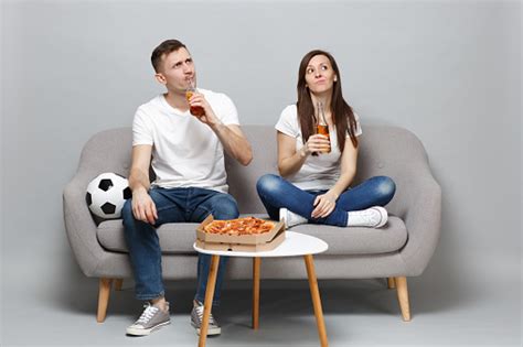 잠겨있는 커플 여자 남자 축구 팬은 회색 벽 배경에 고립 된 맥주 병을 들고 축구 공 지원 좋아하는 팀을 응원 사람들의 감정 스포츠 가족 레저 라이프 스타일 개념입니다