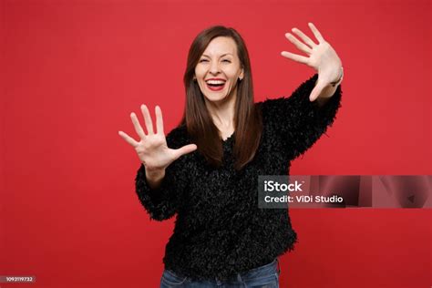 검은 모피 스웨터 서 카메라에 손바닥을 보여주는에 쾌활 한 젊은 여자의 초상화 스튜디오에서 밝은 빨간 벽 배경에 고립 사람들이 진심으 감정 라이프 스타일 개념 복사 공간을