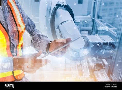 Worker Using Tablet Control Robot Arm In Production Line For Robotic Engineering Concept Stock