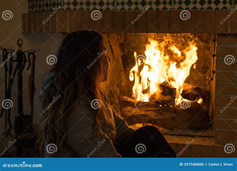 Latina Woman Sitting In Front Of The Fireplace In Cold Winter Stock