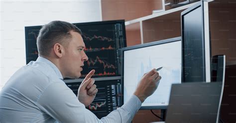 세부 사항에주의하십시오 인덱스 차트에 여러 컴퓨터 화면이 있는 사무실에서 온라인으로 작업하는 남자 사진 Unsplash의