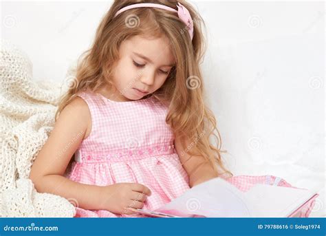 Книга Rad ребенка девушки в кровати одетой в пинке Стоковое Фото изображение насчитывающей