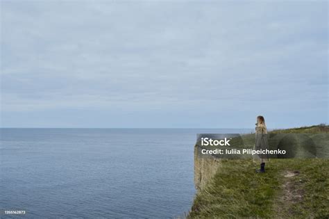 소녀는 절벽 가장자리에 서서 바다 또는 바다를 바라봅니다 여자는 거리를 바라본다 놀라운 경치 자연 보기 아름다운 바위와 바다 조화 편안한 라이프 스타일 여행 모험 가을에