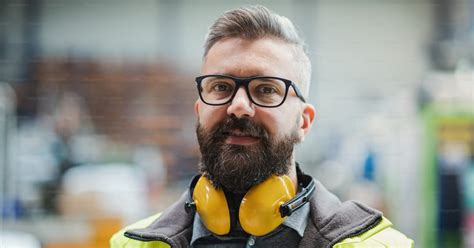 보호 헤드폰을 착용한 기술자 또는 엔지니어가 산업 공장에 서서 카메라를 보고 있습니다 사진 Unsplash의 사진술 이미지