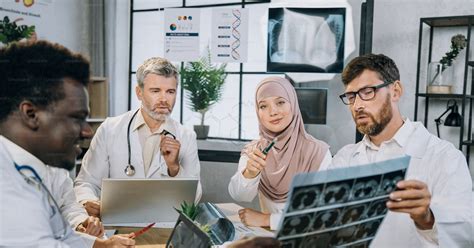 환자의 엑스레이 스캔을 검사하는 테이블에 현대적인 장치를 가진 유능한 다인종 의사 진단을 위해 협력하는 다양한 치료사 그룹 건강 치료 및 의학 개념 사진