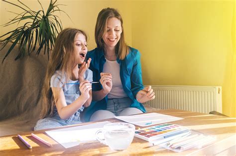 어머니와 딸이 그림을 그립니다 미술 교사는 수채화 물감 구 아슈를 적용하는 기술을 가르치고 브러시를 올바르게 잡는 방법을