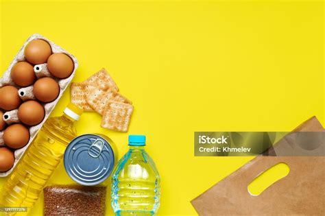 음식 용품 빵 부스러기 비스킷 메밀 계란 물 플라스틱 병 통조림 상품 검역 기간 동안 해바라기 기름 종이 봉투와 노란색 배경 복사 공간을 참조하십시오 플랫레이 Charity