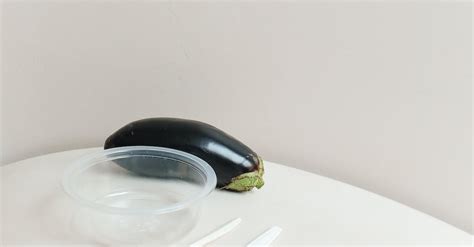 Empty Plastic Container Between Eggplant And Plastic Spoon And Fork