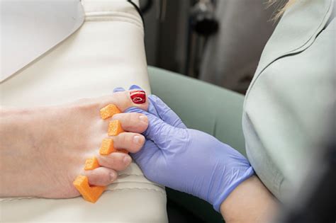 뷰티 살롱의 페디큐어 마스터는 빨간 아크릴 젤로 여성의 발톱을 덮습니다 절차 관리와 보살핌 디자인에 대한 스톡 사진 및 기타