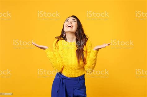 스웨터에 재미 쾌활 한 젊은 여자 파란 바지는 옆에 노란 오렌지 벽 배경에 고립 가리키는 손을 확산 찾고 사람들은 진심으로 감정 라이프 스타일 개념입니다 복사 공간을 모의