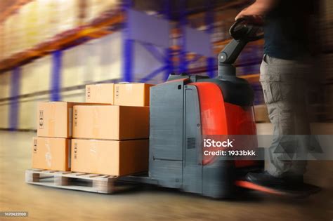 보관 창고의 팔레트에 패키지 상자를 내리는 작업자의 빠른 동작 전동 지게차 팔레트 잭 로더 배송 용품 공급망 선적 상품 유통