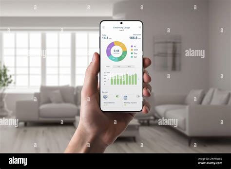 Hand Holds Smartphone With Energy Consumption App In Living Room Interior Concept Of Smart Home