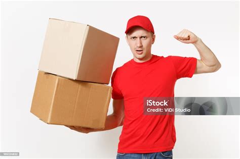 배달 강한 남자 빨간색 유니폼에 흰색 배경에 고립 남자 모자 T셔츠 택배 보여주는 팔 뚝 근육 빈 골 판지 상자를 들고 수신 패키지입니다 광고에 대 한 공간을 복사 합니다