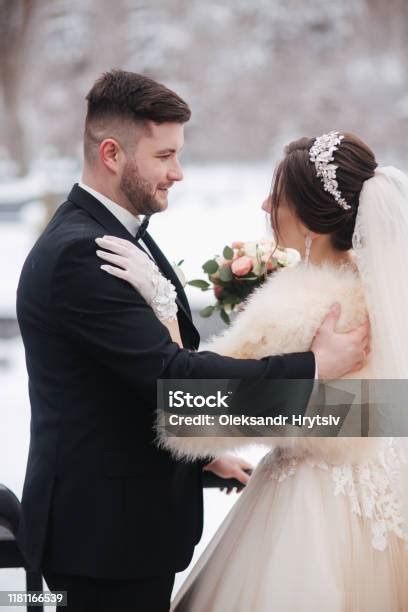 눈 덮인 나무 앞에서 잘 생긴 수염 신랑과 흰색 모피 코트의 우아한 신부 스탠드 겨울에 대한 스톡 사진 및 기타 이미지 겨울 겨울 코트 결혼 의식 Istock