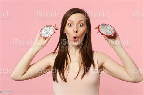 스튜디오에서 분홍색 파스텔 벽 배경에 고립 된 신선한 잘 익은 피타 하 야 드래곤 과일의 두 Halfs 손을 잡고 젊은 여자를 놀라게 사람들은 생생한 라이프 스타일 휴식