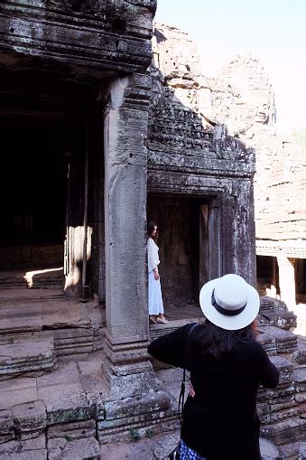 흰 모자와 검은 색 스웨터에 있는 여성은 고 대 유적을 찾습니다 여자는 사진 작가를 위한 포즈 소녀를 검사 합니다 2명에 대한 스톡 사진 및 기타 이미지 Istock