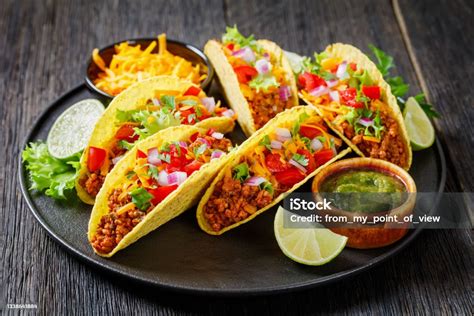 분쇄 치즈를 곁들인 갈은 쇠고기 타코 그린 살사 베르데 소스 신선한 양상추 토마토 라임이 있는 검은 접시에 양파 비프 타코에 대한 스톡 사진 및 기타 이미지 Istock