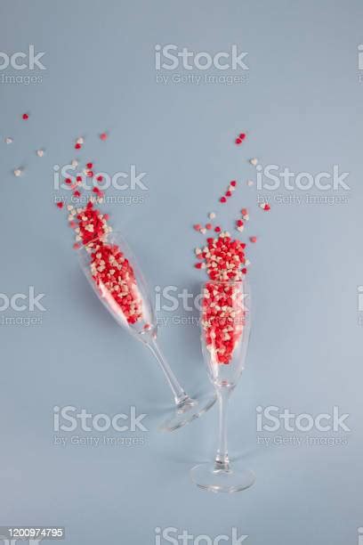 빨간 하트 모양의 설탕 사탕의 스플래시와 두 개의 샴페인 안경 파란색 배경 위에 발렌타인 데이 기념일 또는 결혼 축하 개념입니다 플랫 레이 맨 위 보기 공간을 복사합니다