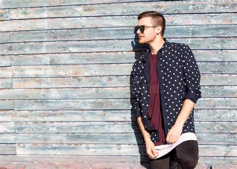 Fashion Guy In Glasses Poses Near A Wooden Wall In Blue Stock Image