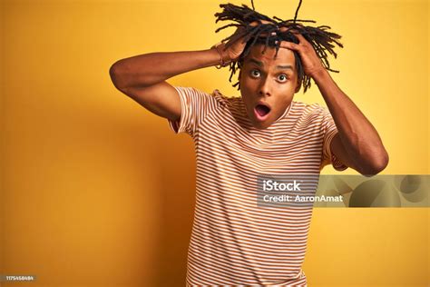 고립 된 노란색 배경 미친 위에 서 줄무늬 티셔츠를 입고 공포를 가진 아프로 남자 미친 머리에 손을 무서워 두려워하고 열린