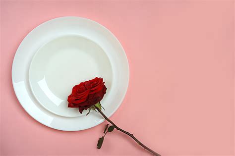 상위 뷰 발렌타인 또는 저녁 식사 날짜 축제 결혼식을 위한 로맨틱 테이블 설정입니다 레드 테이블 설정 빨간색 식탁보 핑크 파스텔 컬러 배경에 버드 화이트 접시 포크와