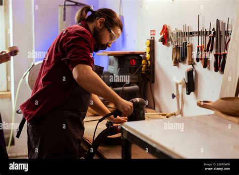 Carpenter Using Angle Grinder On Timber Block To Smooth Surfaces By