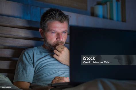 매력적이 고 편안한 인터넷 중독자 젊은이 네트워킹 소셜 미디어 중독 또는 중독 사업 개념에 노트북 컴퓨터와 함께 침대에 밤에 집중 포르노에 대한 스톡 사진 및 기타 이미지