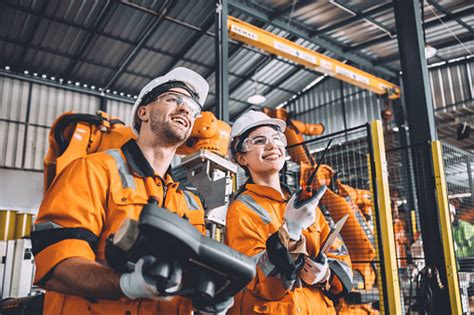 자동화 공장에서 로봇 용접을 담당하는 엔지니어 팀 안전복을 입은 사람들은 자동화된 제조 산업 기술에서 로봇 팔을 제어합니다 20