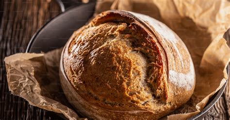 갓 구운 바삭 바삭한 소박한 효모 빵이 밀알 나무 국자로 가득 찬 합금 팬 나무 그릇에 베이킹 페이퍼 위에 누워 깊숙이 꿰매어졌습니다 사진 Unsplash의 빵 이미지