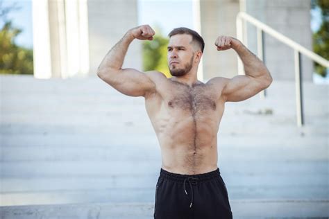 裸の体を外でポーズをとる若い筋肉強い男性アスリート Premium写真