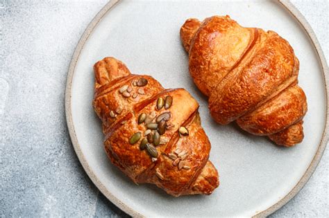 갓 구운 수제 크루아상으로 구성된 조식 클로즈업 콘크리트 또는 돌 배경에 회색 접시에 호박 씨앗과 전통 과 통곡물 크루아상