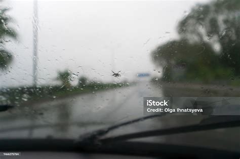 비오는 날씨에 날아 다니는 돌에서 자동차의 깨진 앞 유리 유리 칩 및 파편에 구멍 스트립에 균열 빗방울이있는 돌의 충격으로 앞 유리가 손상된 자동차 0명에 대한 스톡 사진