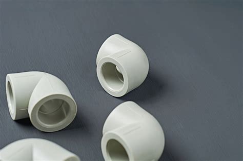 흩어진 폴리 프로필렌 난방 실을위한 물 또는 다른 액체 파이프를 연결하기위한 90도의 플라스틱 모서리는 작업장의 어두운 콘크리트 책상에 놓여 있습니다 텍스트를 위한 공간