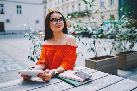 디지털 태블릿 장치를 손에 들고 도심의 야외에 앉아있는 자신의 비즈니스 Stur Tap 프로젝트에 대한 새로운 창조적 인 아이디어를 생각하는 광학 안경의 매력적인 젊은