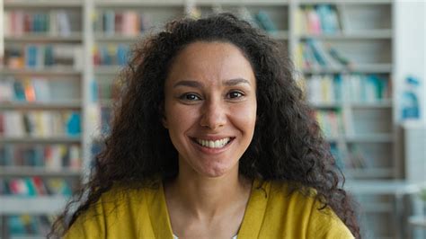 행복 인도인 백인 여자 대학 도서관 책장 미소 웃는 소녀 학생 레이디 카메라를보고 여성 초상화 고등학교 대학 교육 배우다 서점