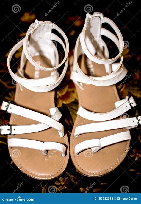 Worn White Summer Sandals With Lots Of Straps Vintage Girl Shoes Top View On Dark Background