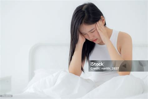 젊은 아시아 여성은 집에서 침실에서 통증 두통 불행한 여성 피로와 아픈 두통 불안과 불쾌감 현기증과 장애 의료 및 건강 개념에 앉아 있습니다 불면증에 대한 스톡 사진 및