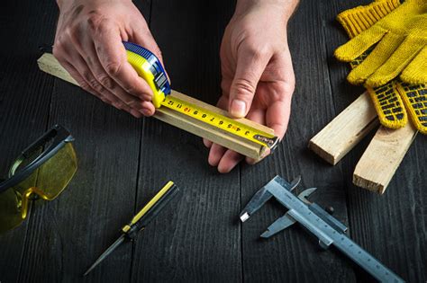 목수 또는 목공인은 건설 테이프를 사용하여 나무 조각의 길이를 측정합니다 직장에서 주인의 손 클로즈업 목공 작업장의 작업 환경 개선에 대한 스톡 사진 및 기타 이미지