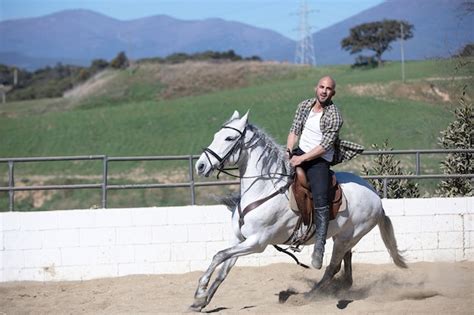 Premium Photo Young Guy In Casual Outfit Riding White Horse On Sandy