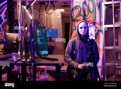 anonymous hacker recording threat video with ransom message on